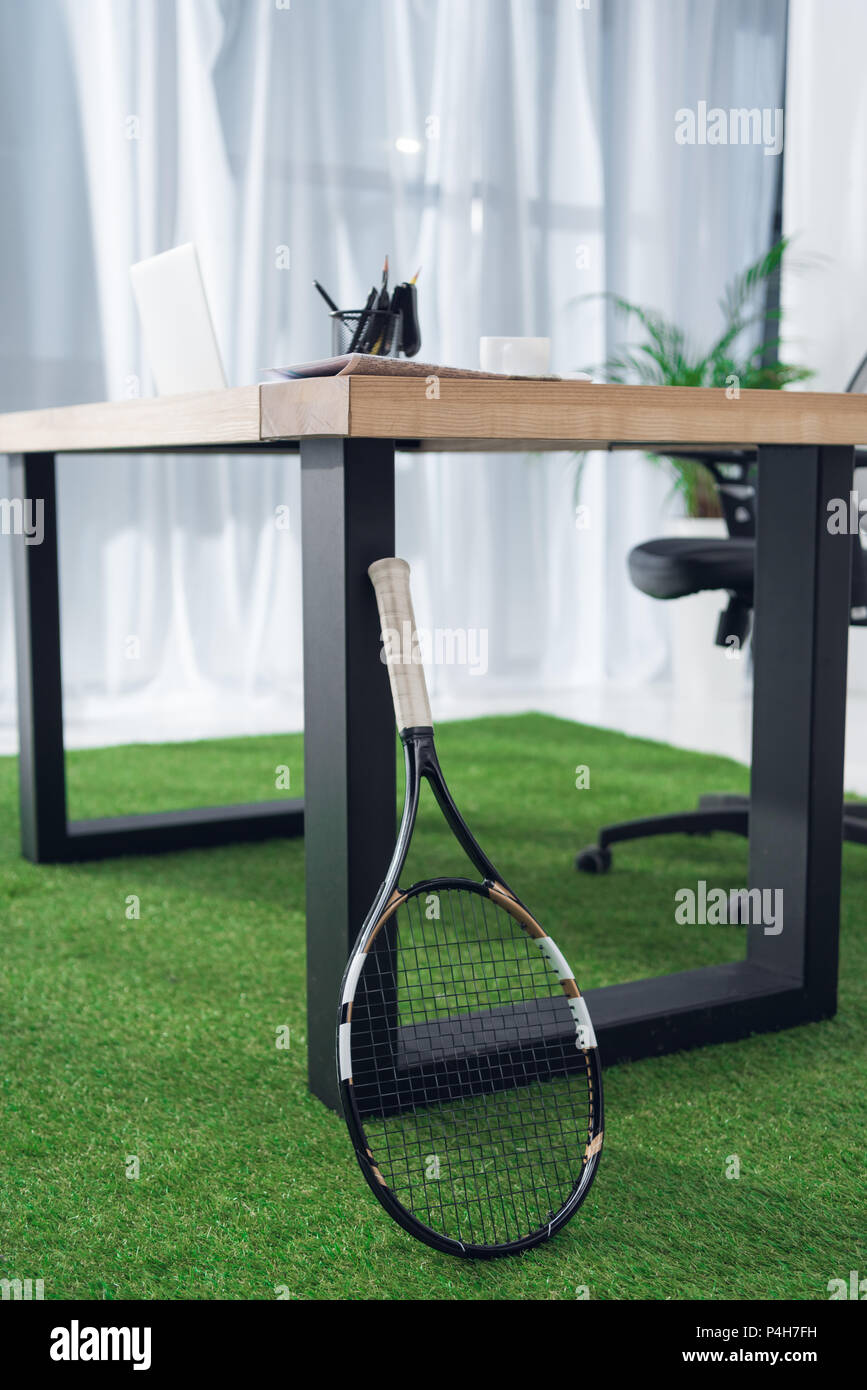 close up view of workplace with laptop and tennis racket in office ...