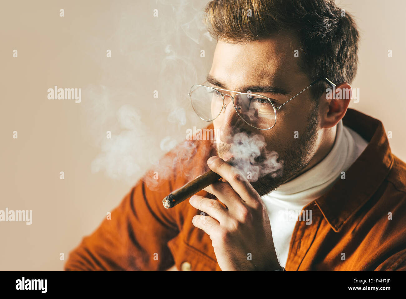 portrait of fashionable pensive man smoking cigar and looking away ...