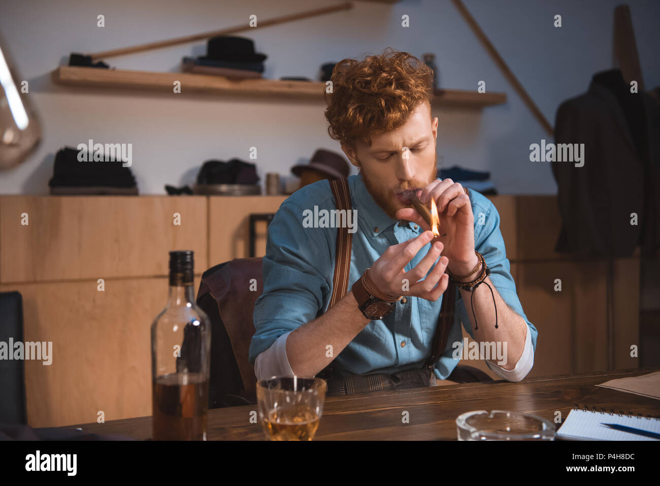 stylish young fashion designer drinking whisky and smoking cigar at ...