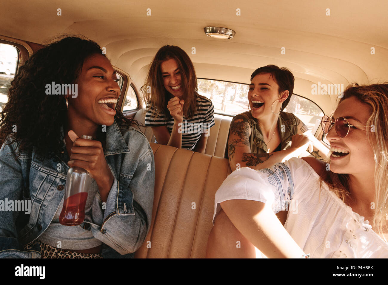 Young friends on a road trip traveling by a car and laughing. Group of ...