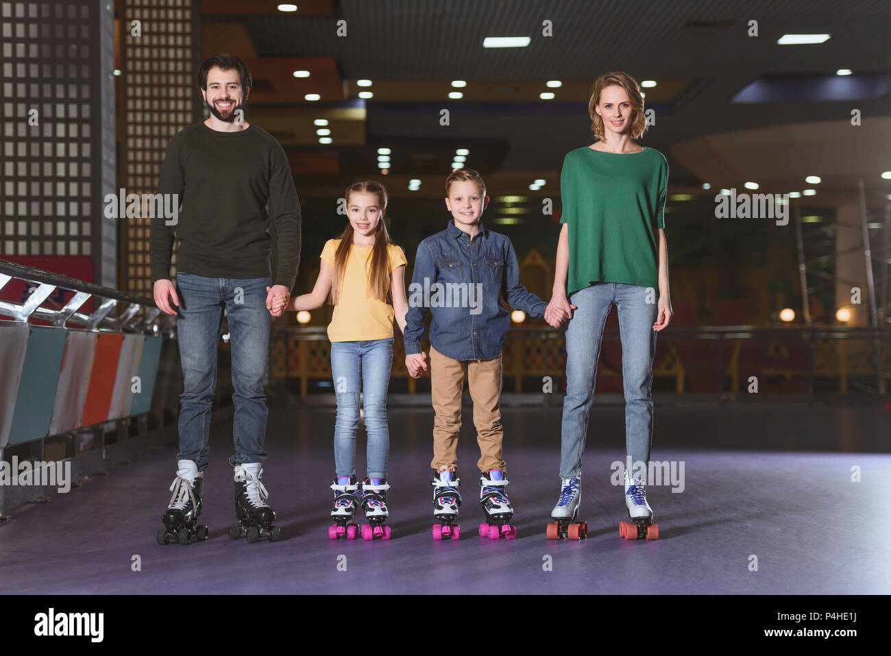happy family holding hands while skating together on roller rink Stock ...