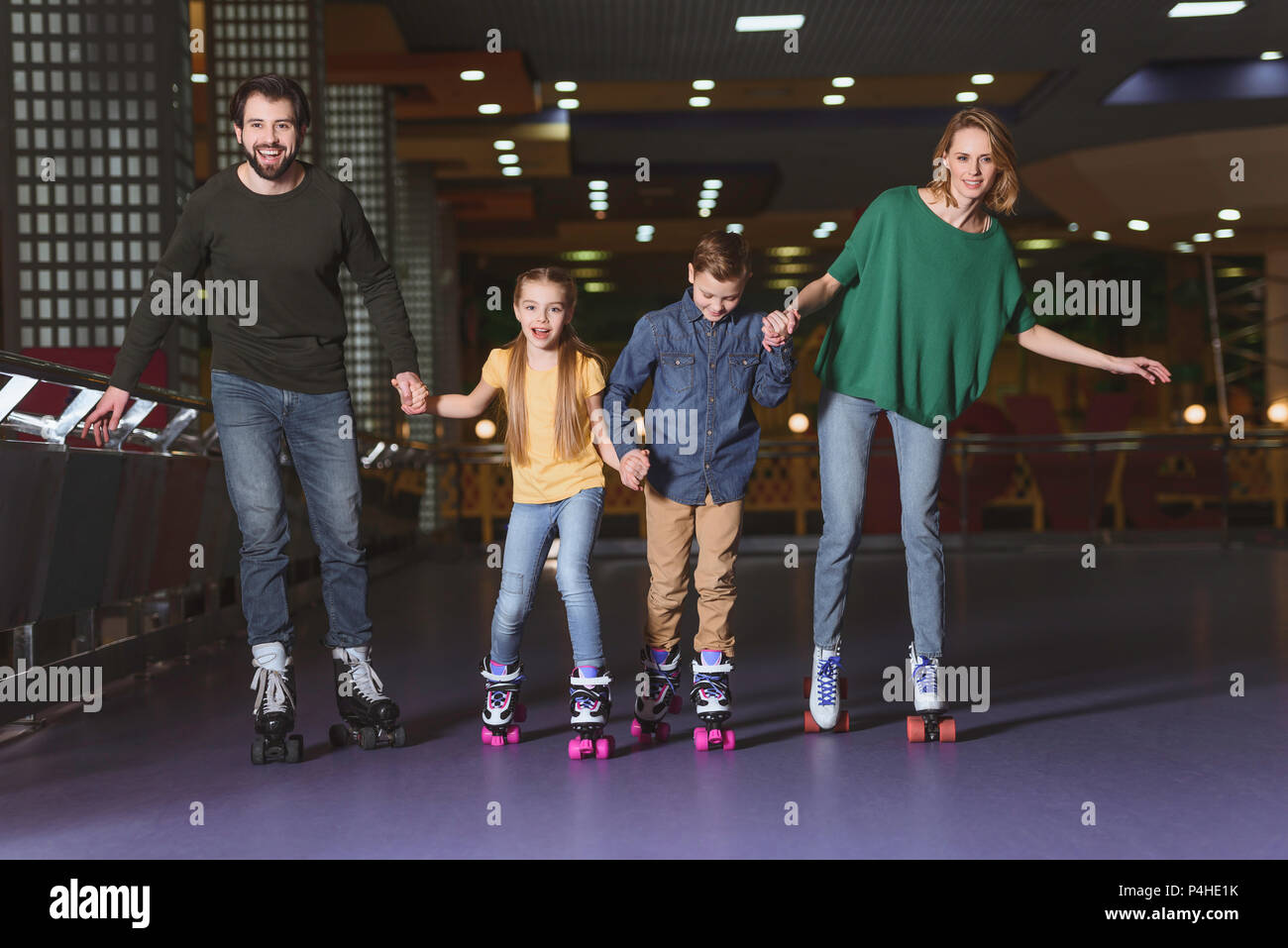 happy family holding hands while skating together on roller rink Stock ...