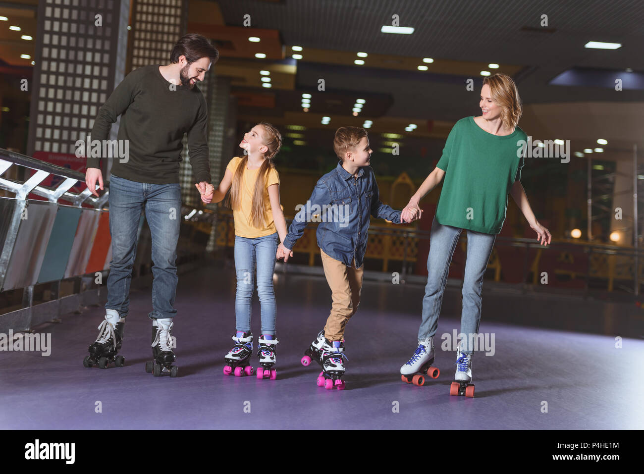 happy family holding hands while skating together on roller rink Stock ...