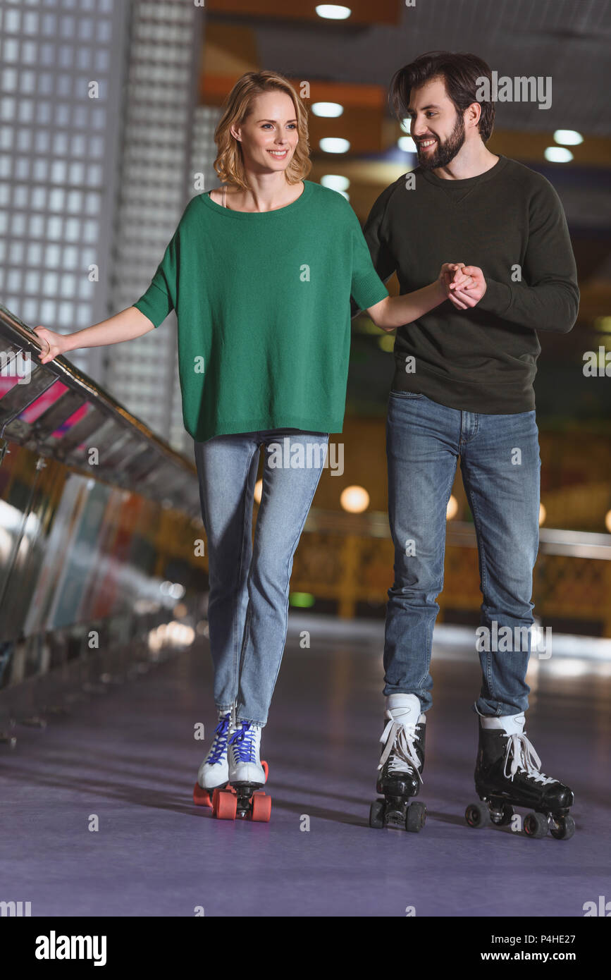 young smiling couple skating together on roller rink Stock Photo - Alamy