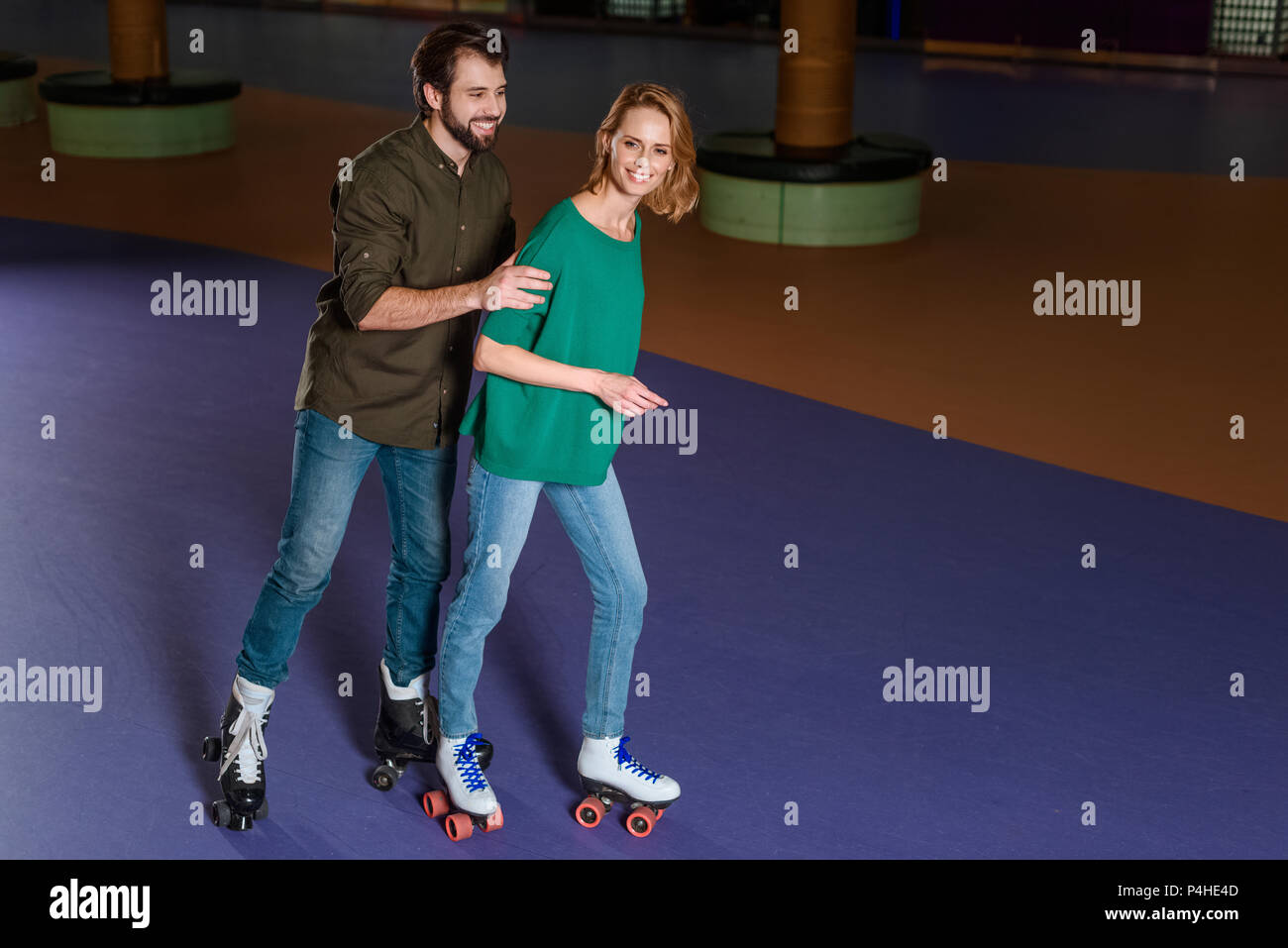 young smiling couple skating together on roller rink Stock Photo - Alamy