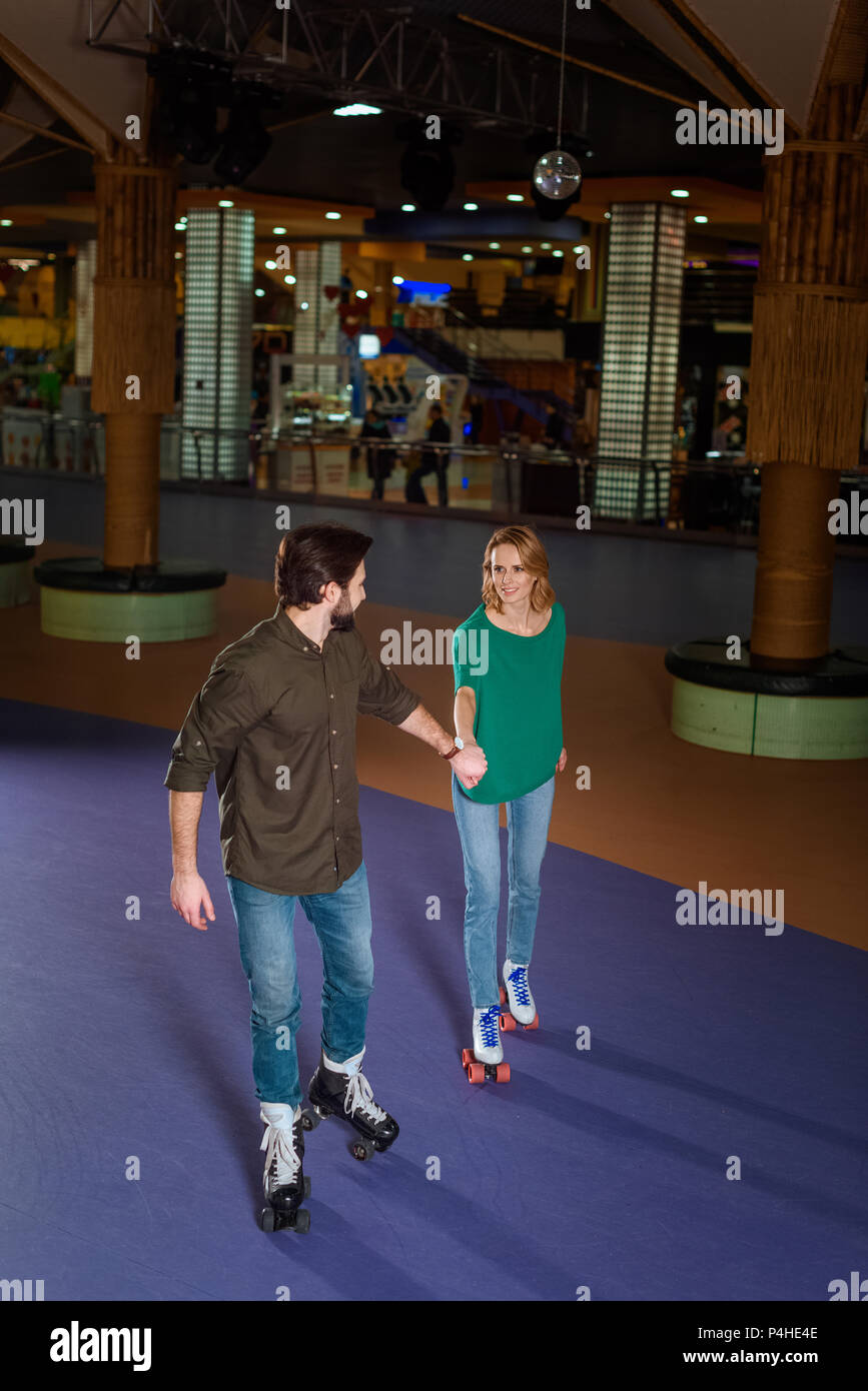 young couple holding hands while skating together on roller rink Stock ...