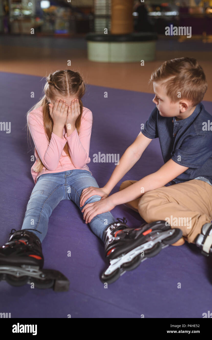 brother cheering up crying sister in roller skates on roller rink Stock ...