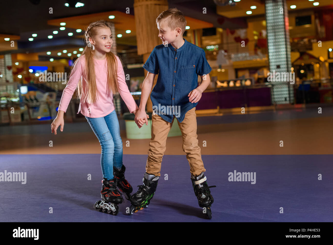 adorable kids holding hands while skating together on roller rink Stock ...
