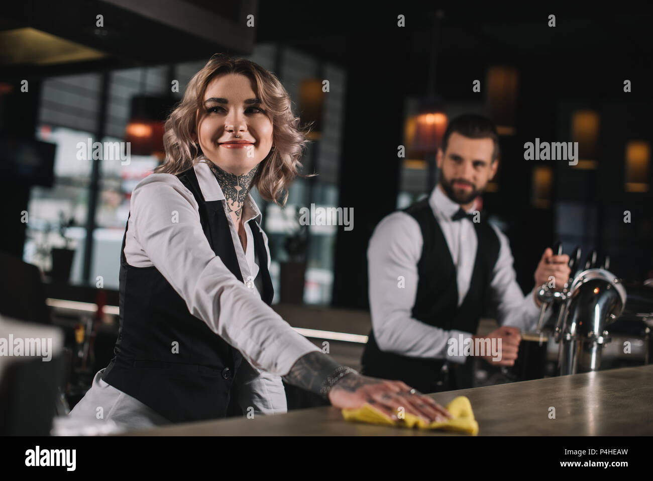 smiling bartender cleaning bar counter and looking away Stock Photo - Alamy