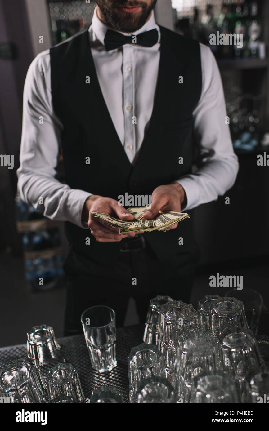 cropped image of bartender counting tips at bar counter Stock Photo - Alamy