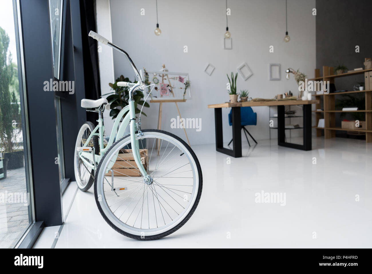 interior of empty creative office with bicycle and workspace at daytime ...