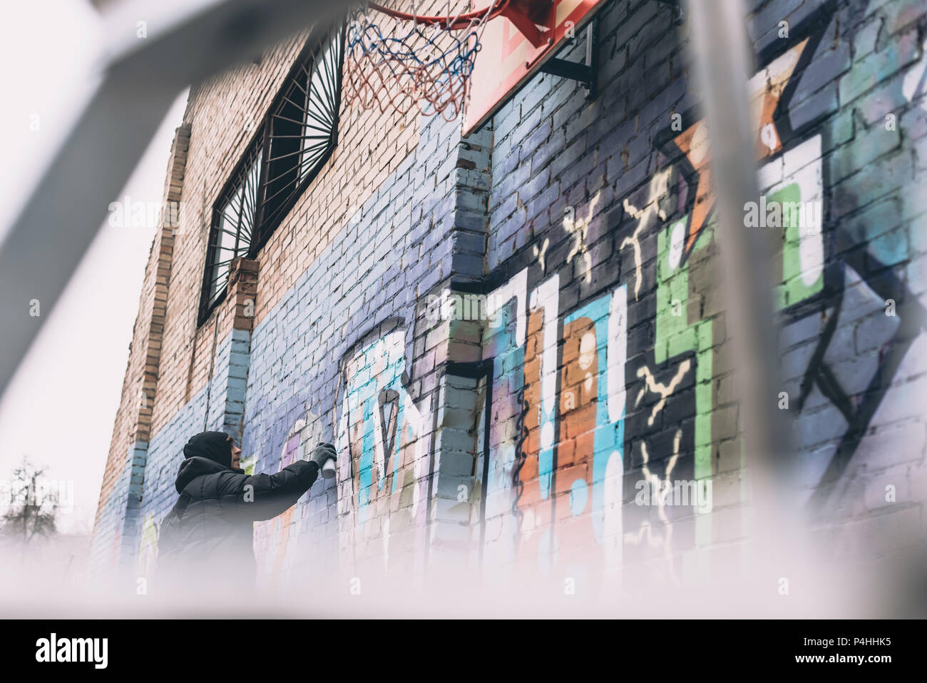 selective focus of street artist painting colorful graffiti on wall ...