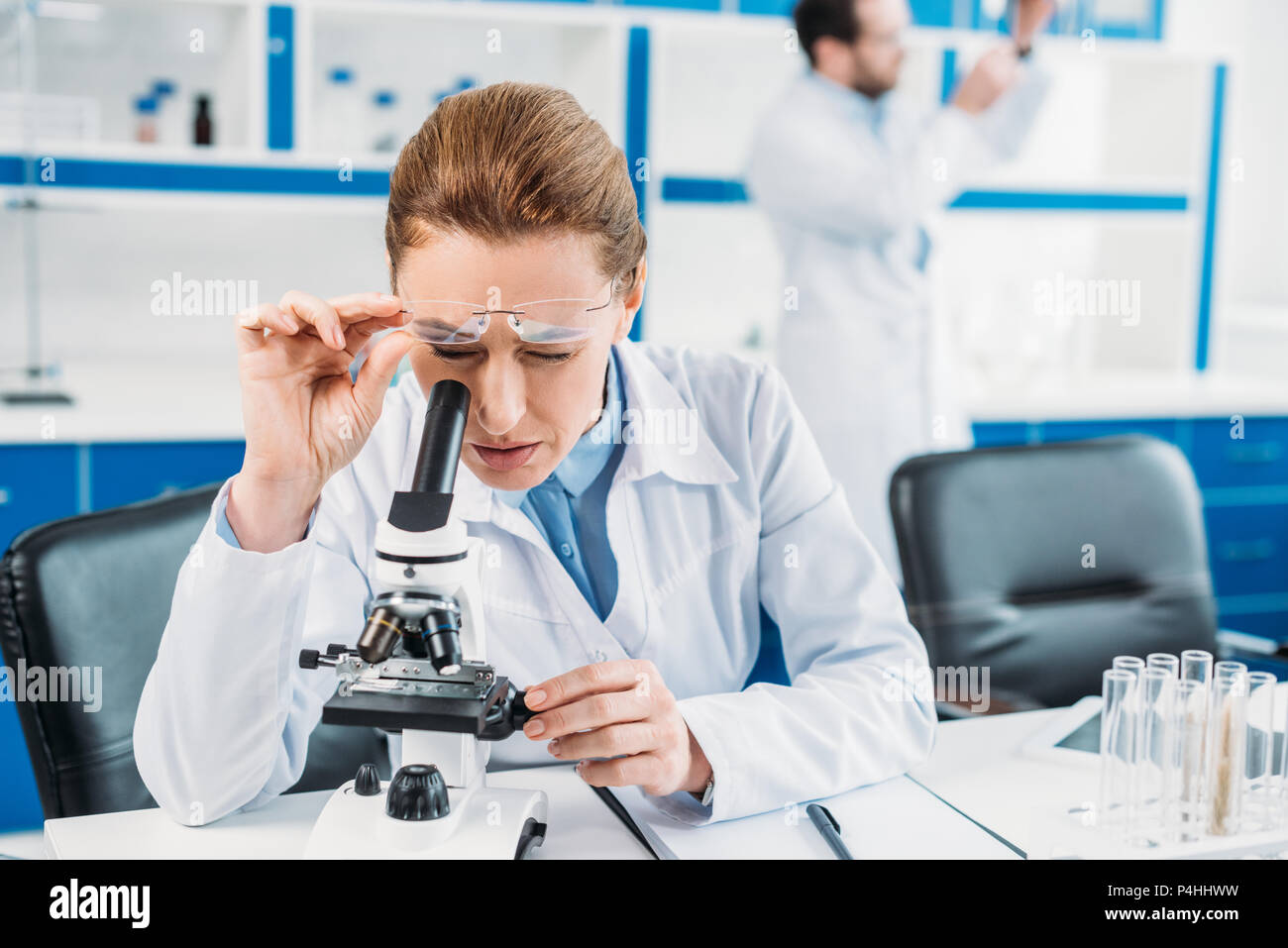 selective focus of female scientist looking through microscope on ...