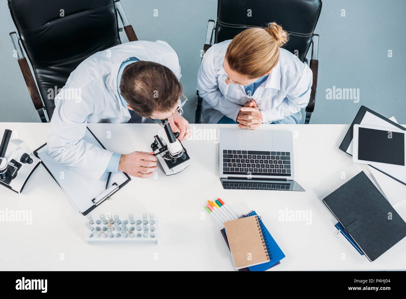 overhead view of scientific researchers in white coats working together ...