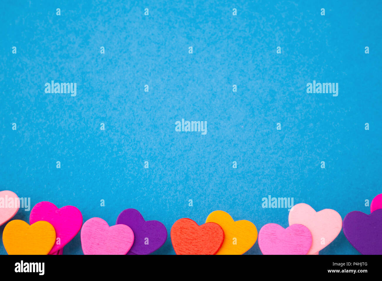 A frame of colored wooden hearts stacked in lovers couples on a blue ...