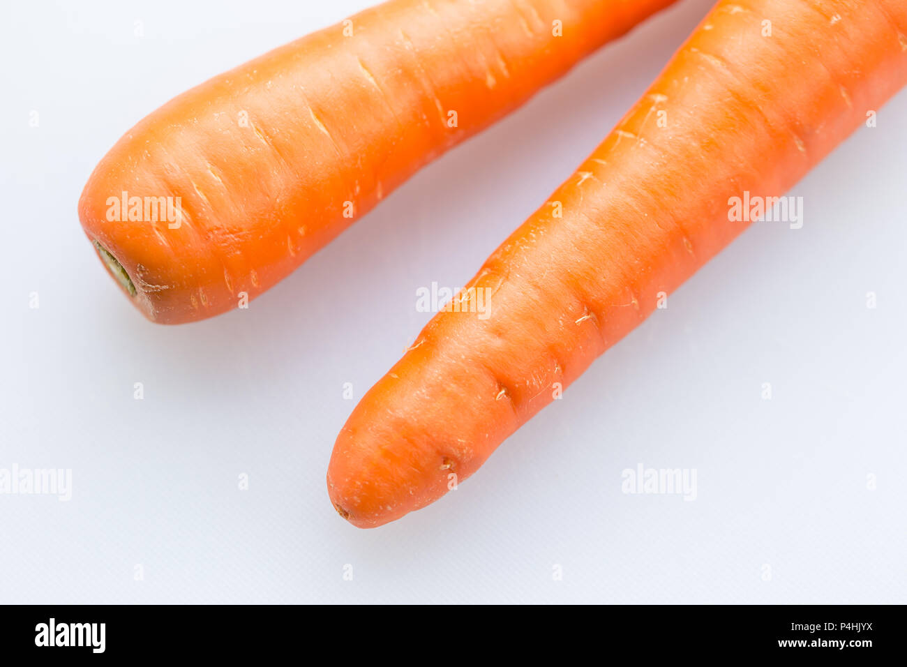 Pair long fresh raw carrot on a plastic cutting board is white color ...