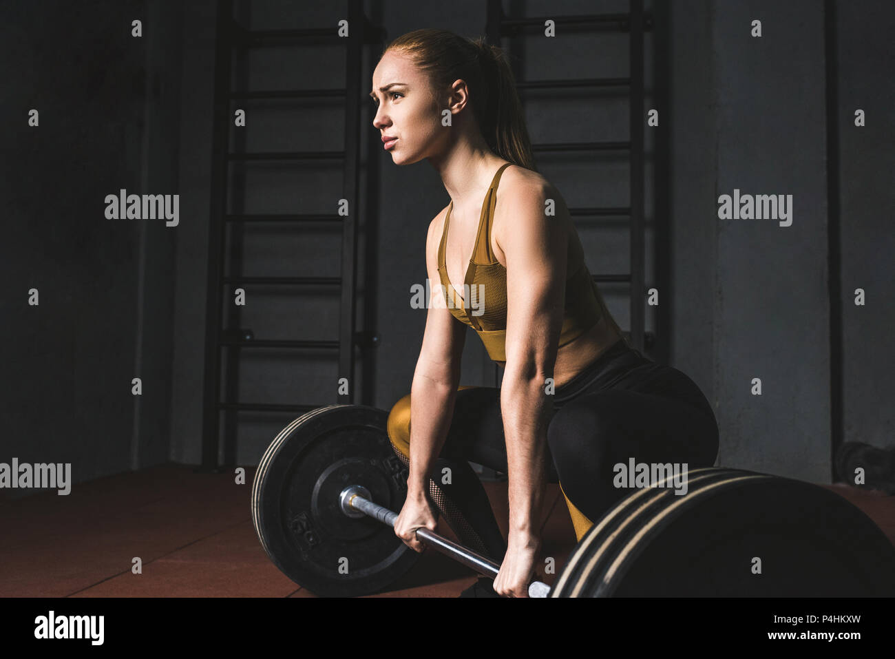 Side view of young bodybuilder preparing to raise barbell in gym Stock ...
