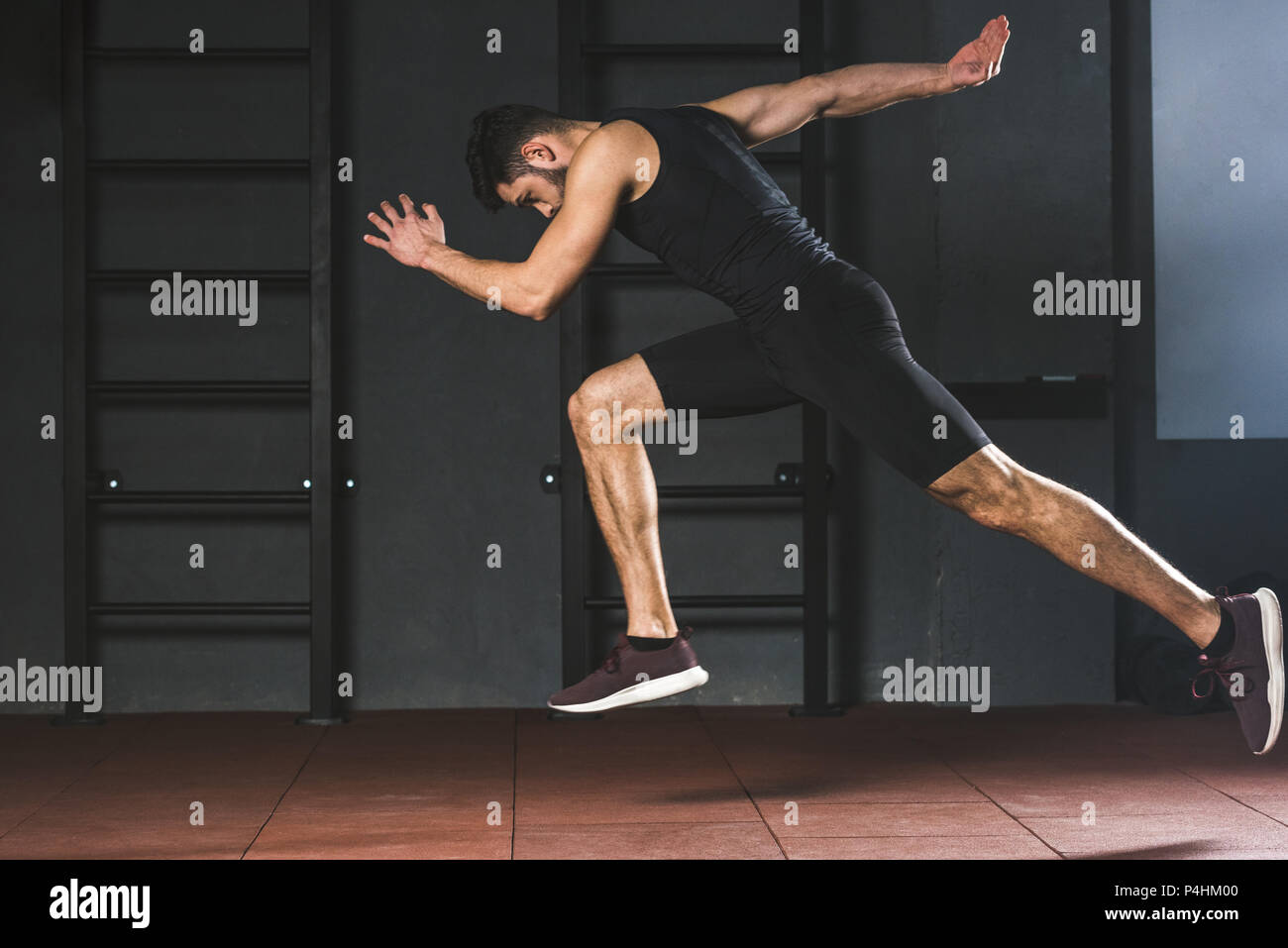 Side view of young sportsman running in sports center Stock Photo - Alamy