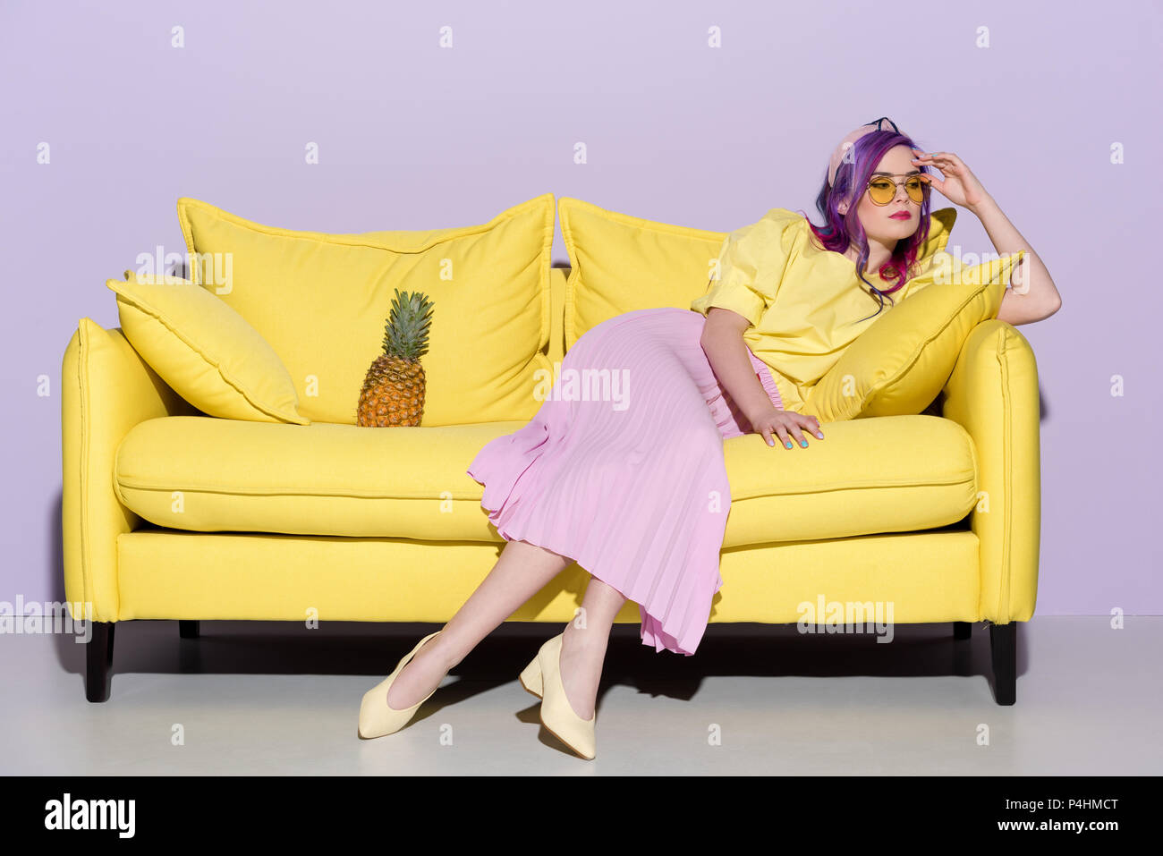 stylish thoughtful woman sitting on yellow couch with pineapple Stock ...