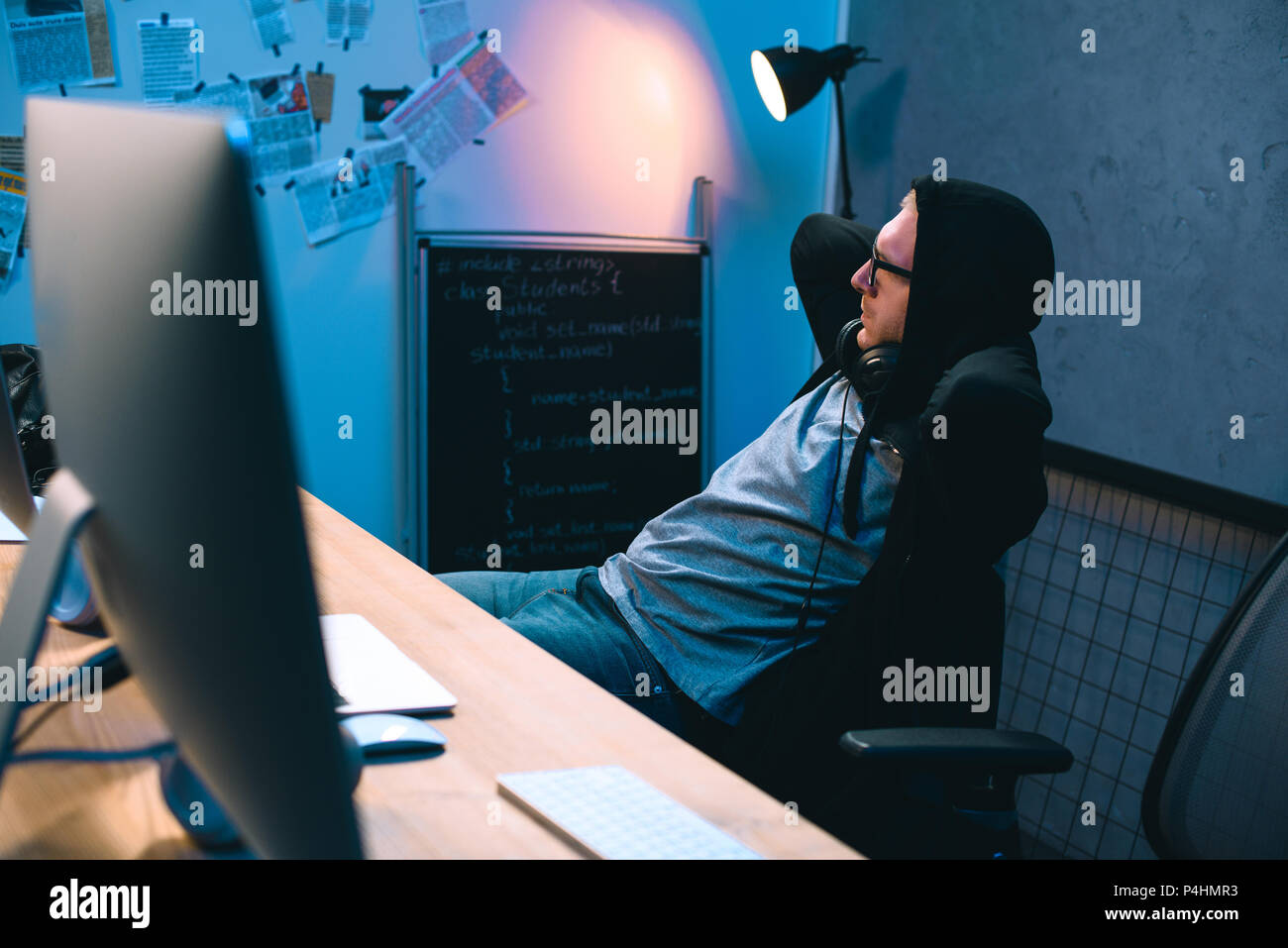 young hooded hacker relaxing on chair in front of his workplace Stock ...