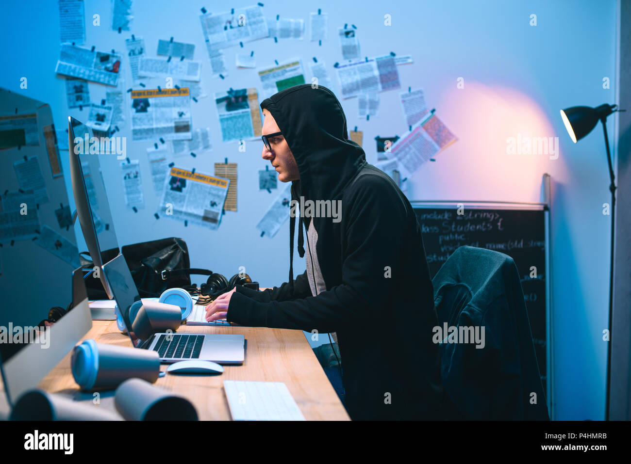 side view of hooded young hacker working with computer Stock Photo - Alamy