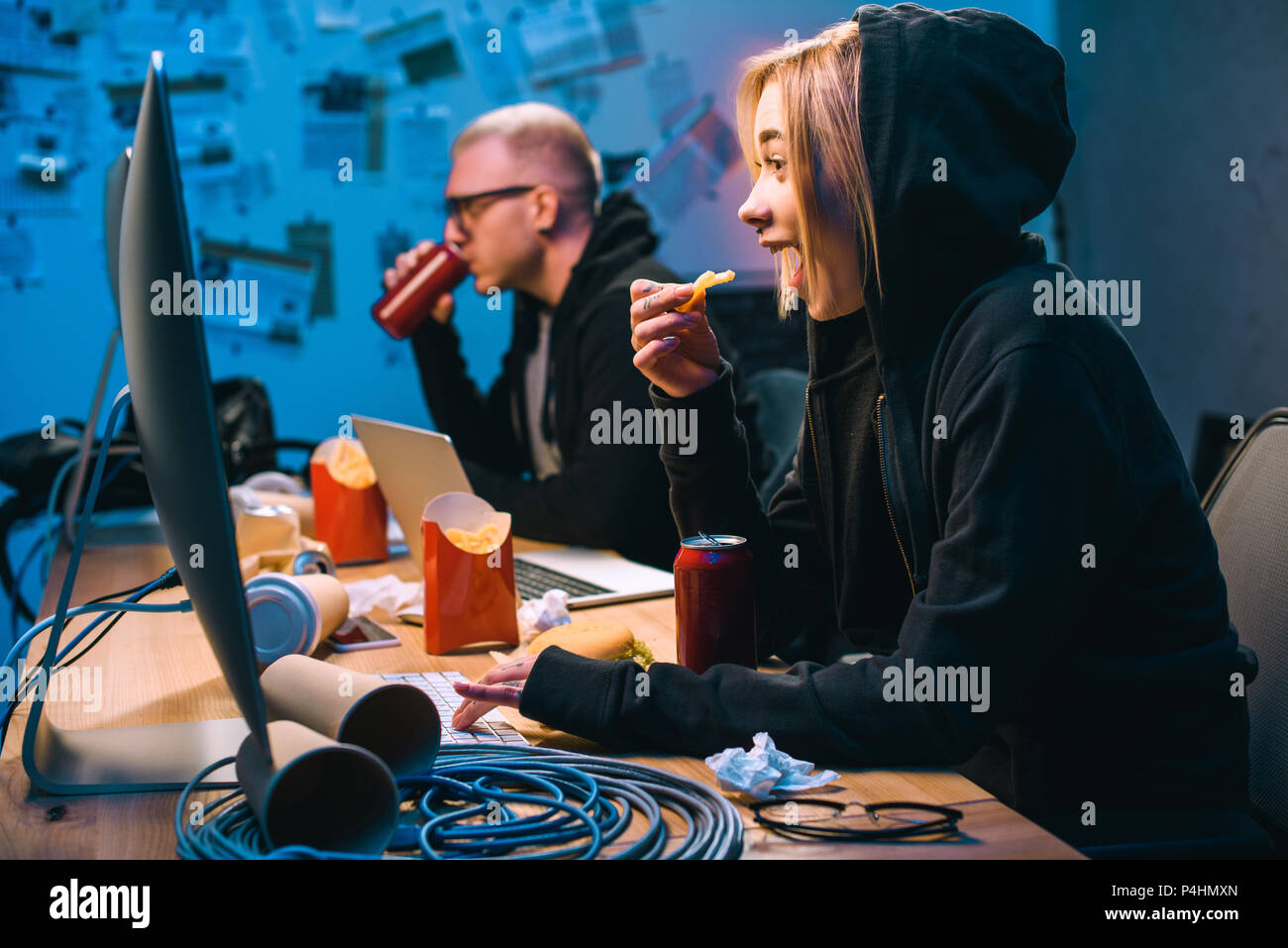 side view of hackers eating junk food while working on malware Stock ...
