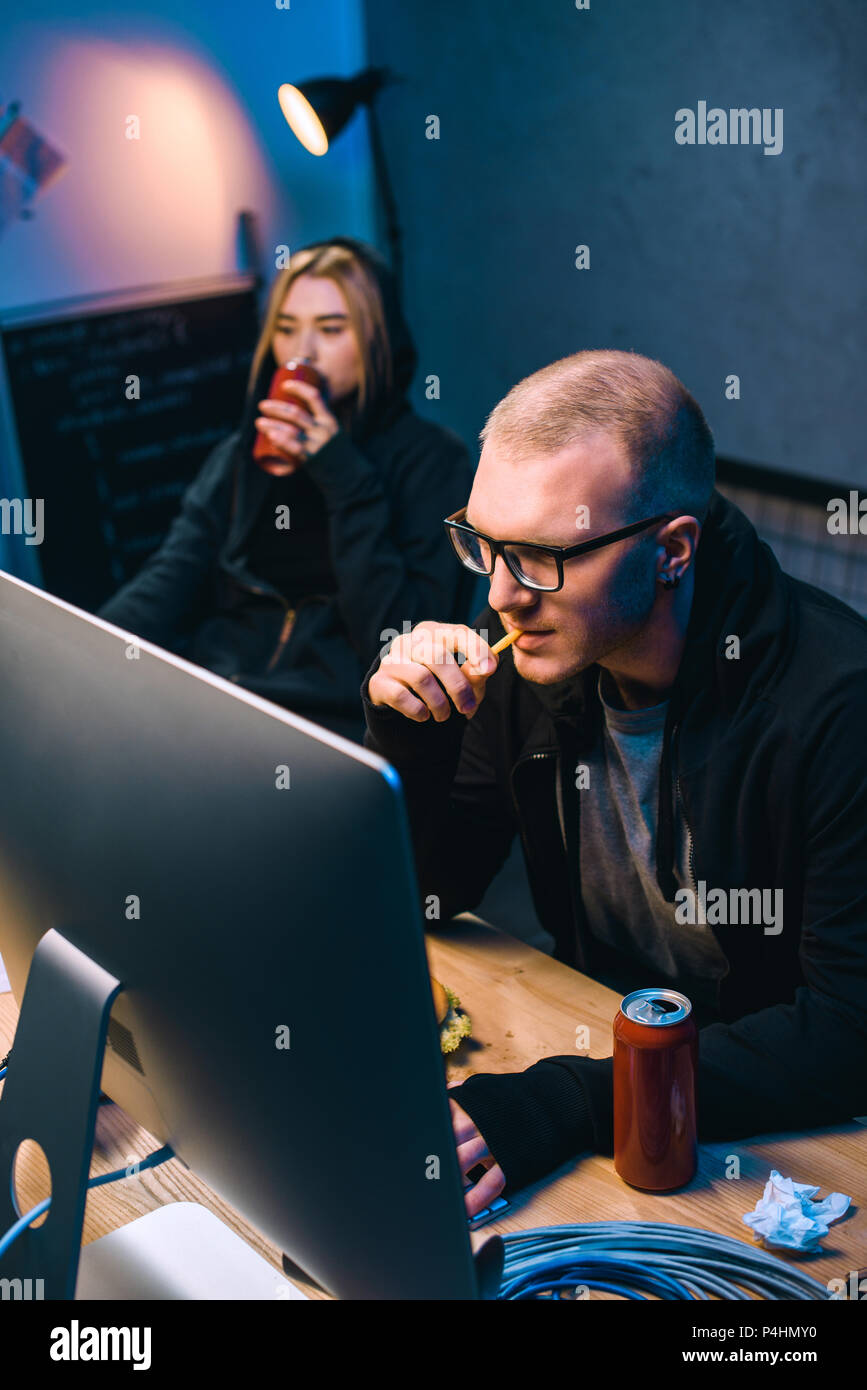 young hackers drinking beer and eating junk food while working on ...