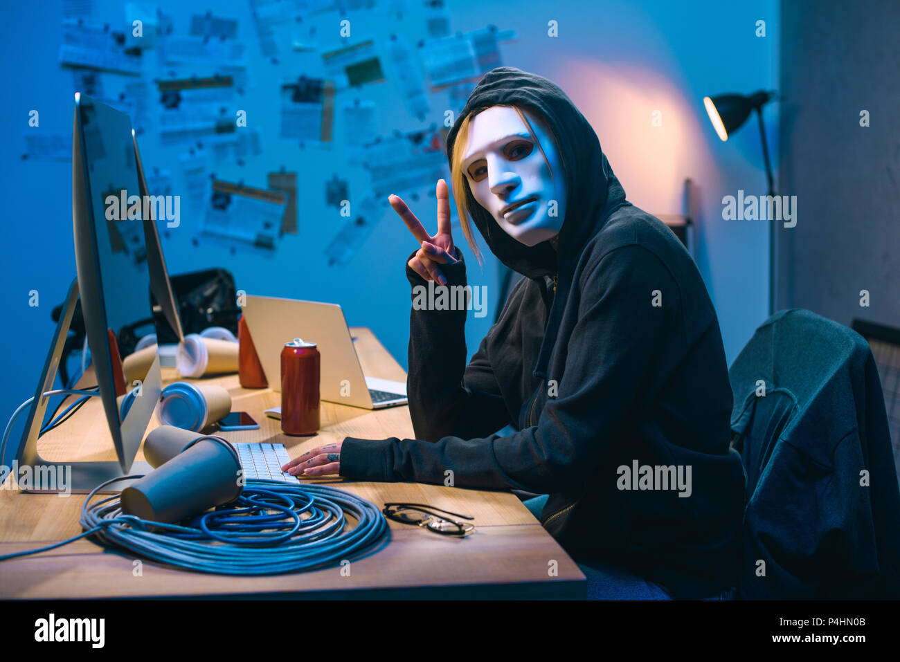 female hacker in mask showing v sign at workplace Stock Photo - Alamy