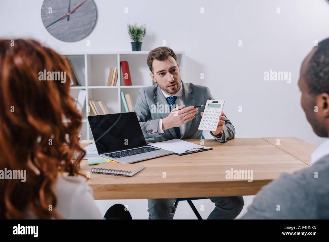 Financial adviser showing calculation while clients sitting at table ...