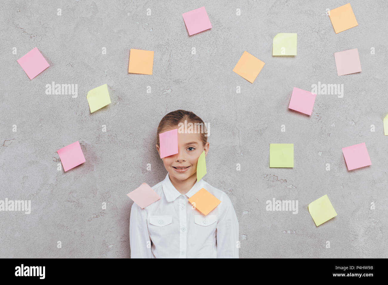 portrait of smiling little girl with empty sticky notes on face ...