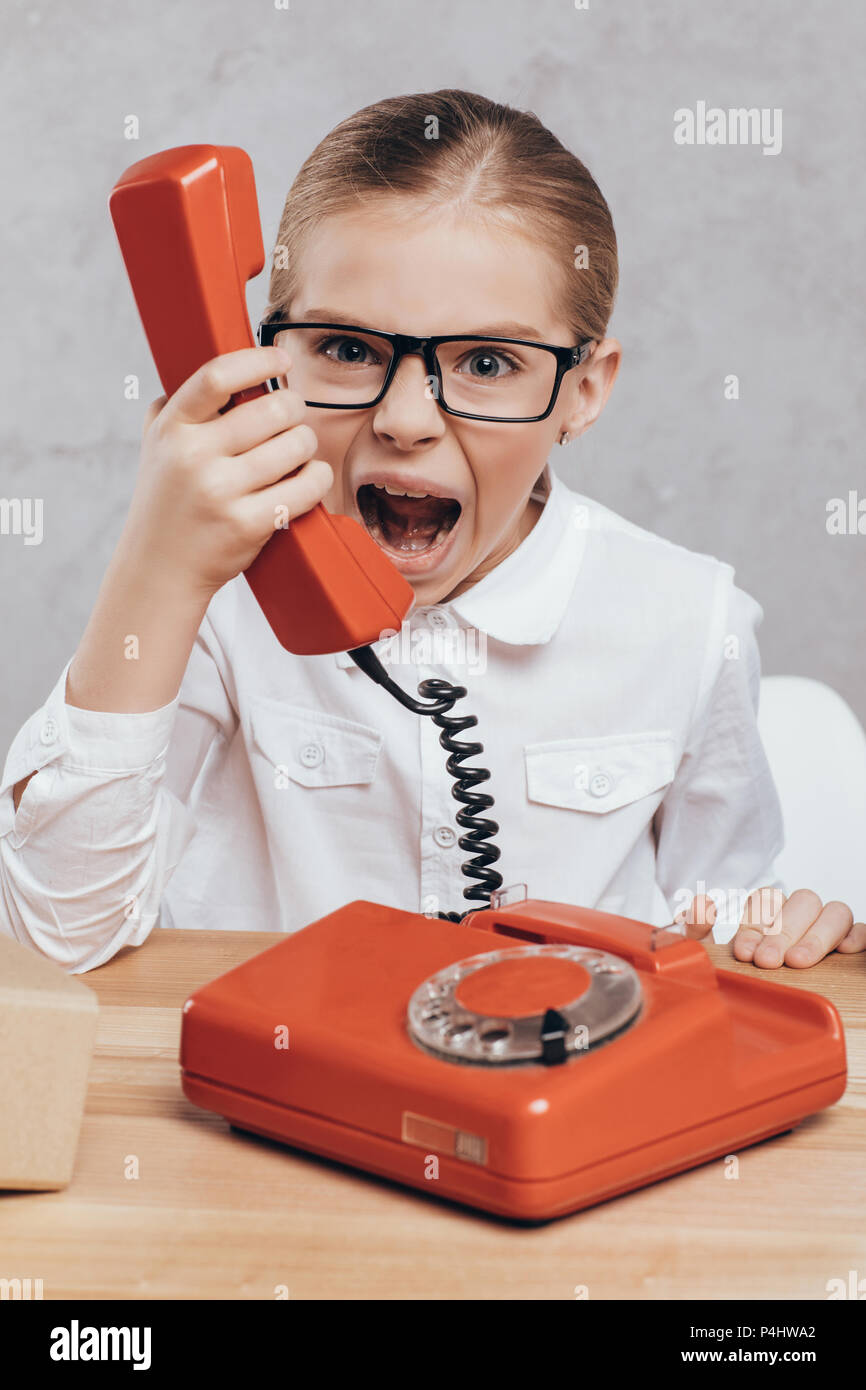 portrait of little girl screaming into telephone tube at workplace ...