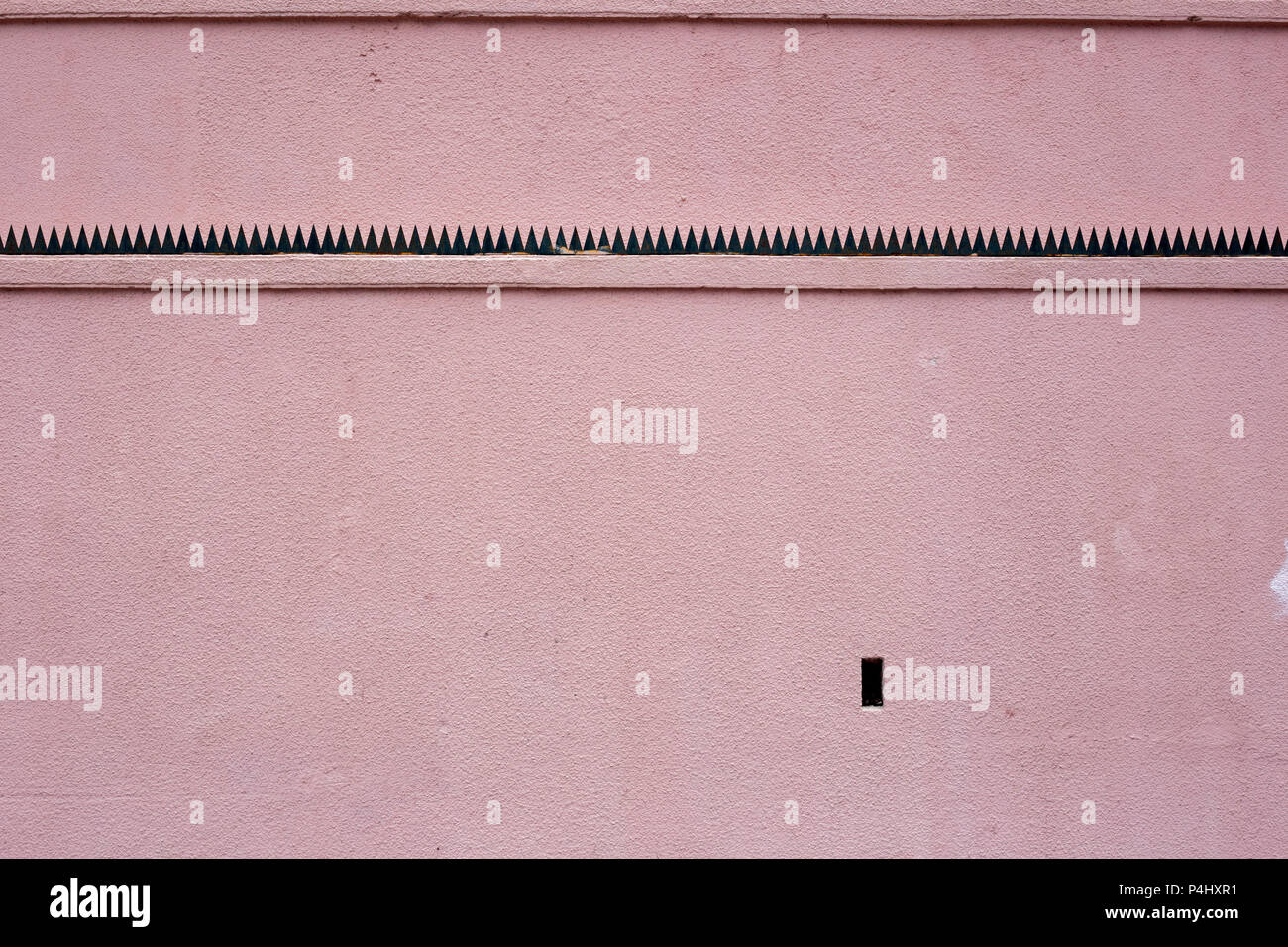 Texture background showing a pink painted wall with a row of anti climb ...