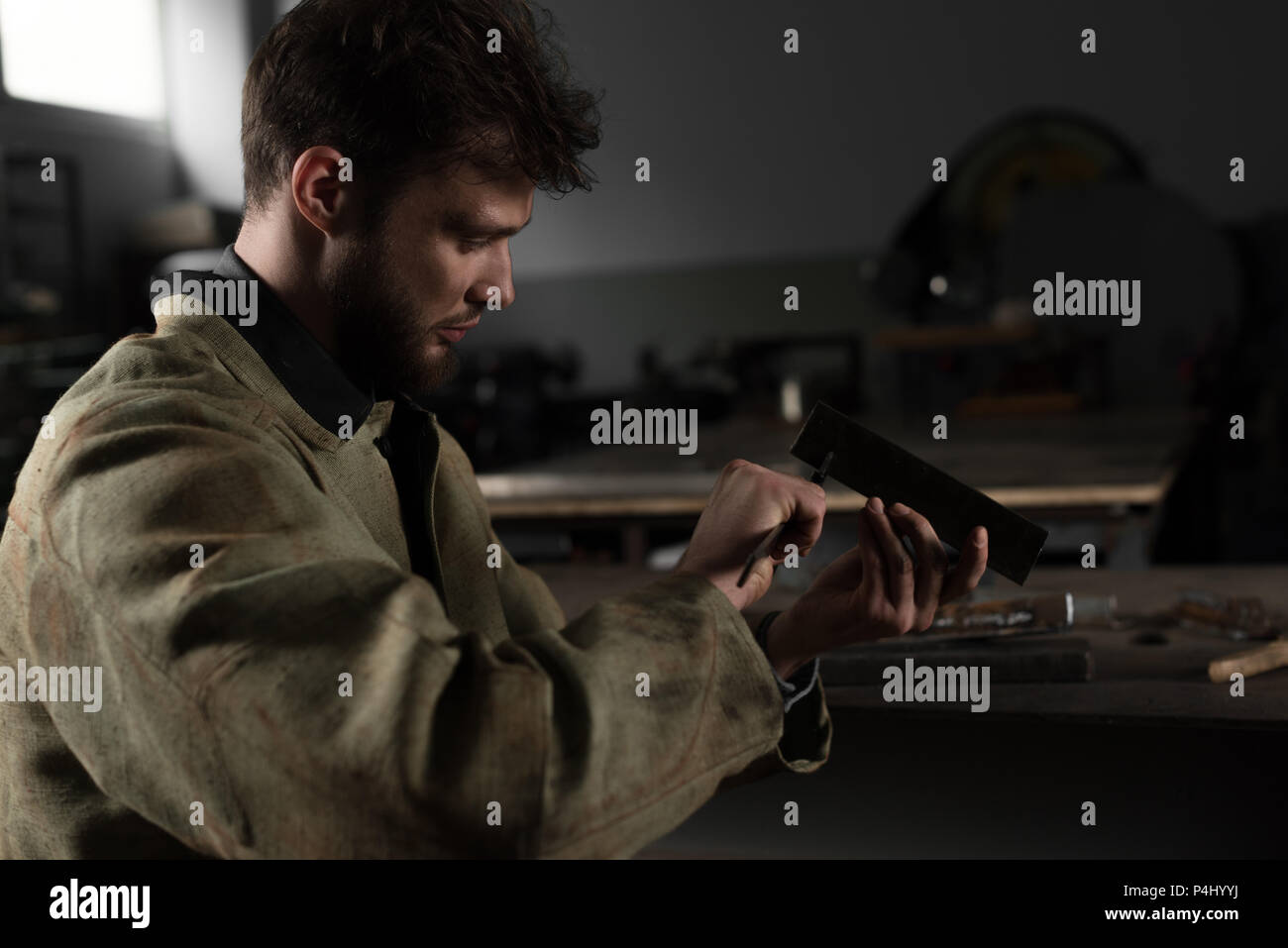 side view of young male worker measuring metal part at factory Stock ...