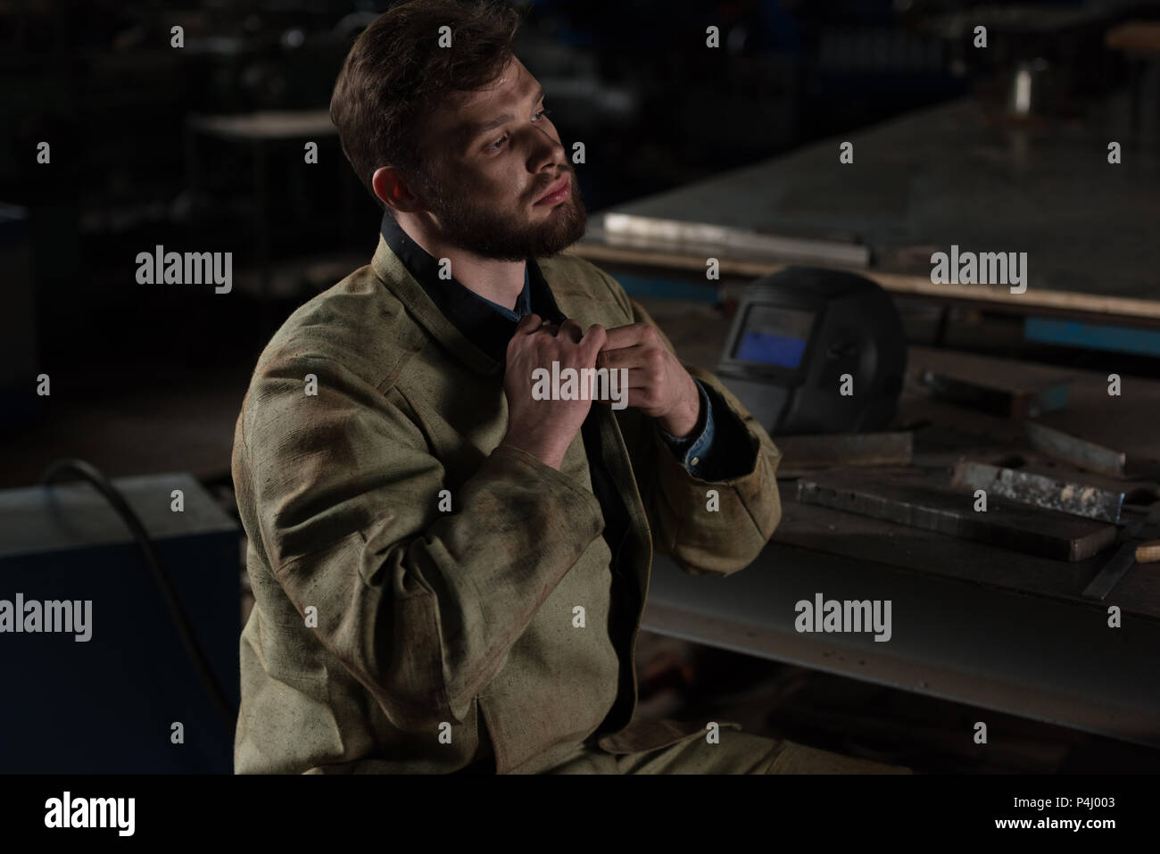 young male worker buttoning up his uniform at factory Stock Photo - Alamy