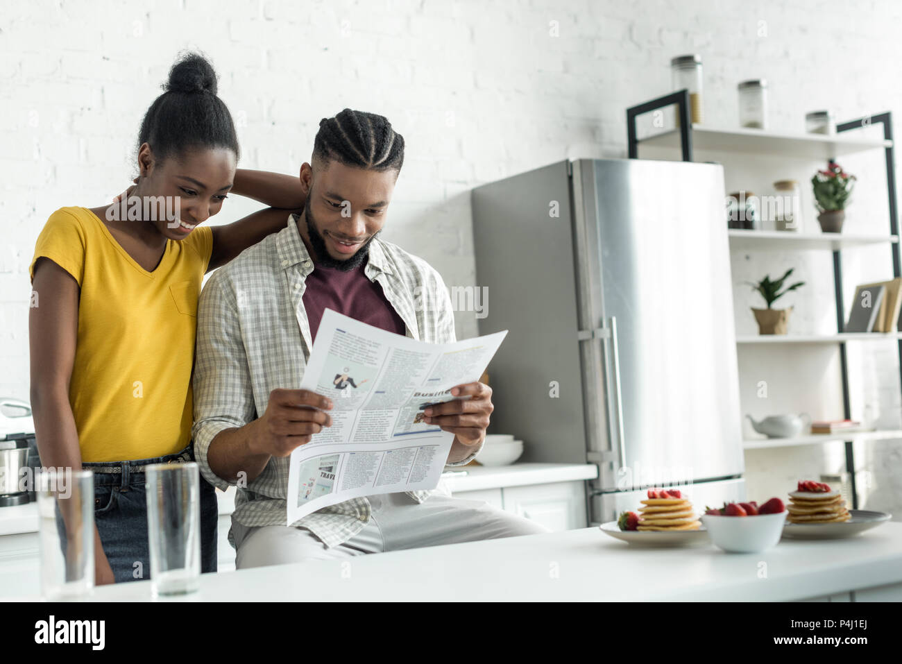african american couple reading newspaper together at kitchen Stock ...