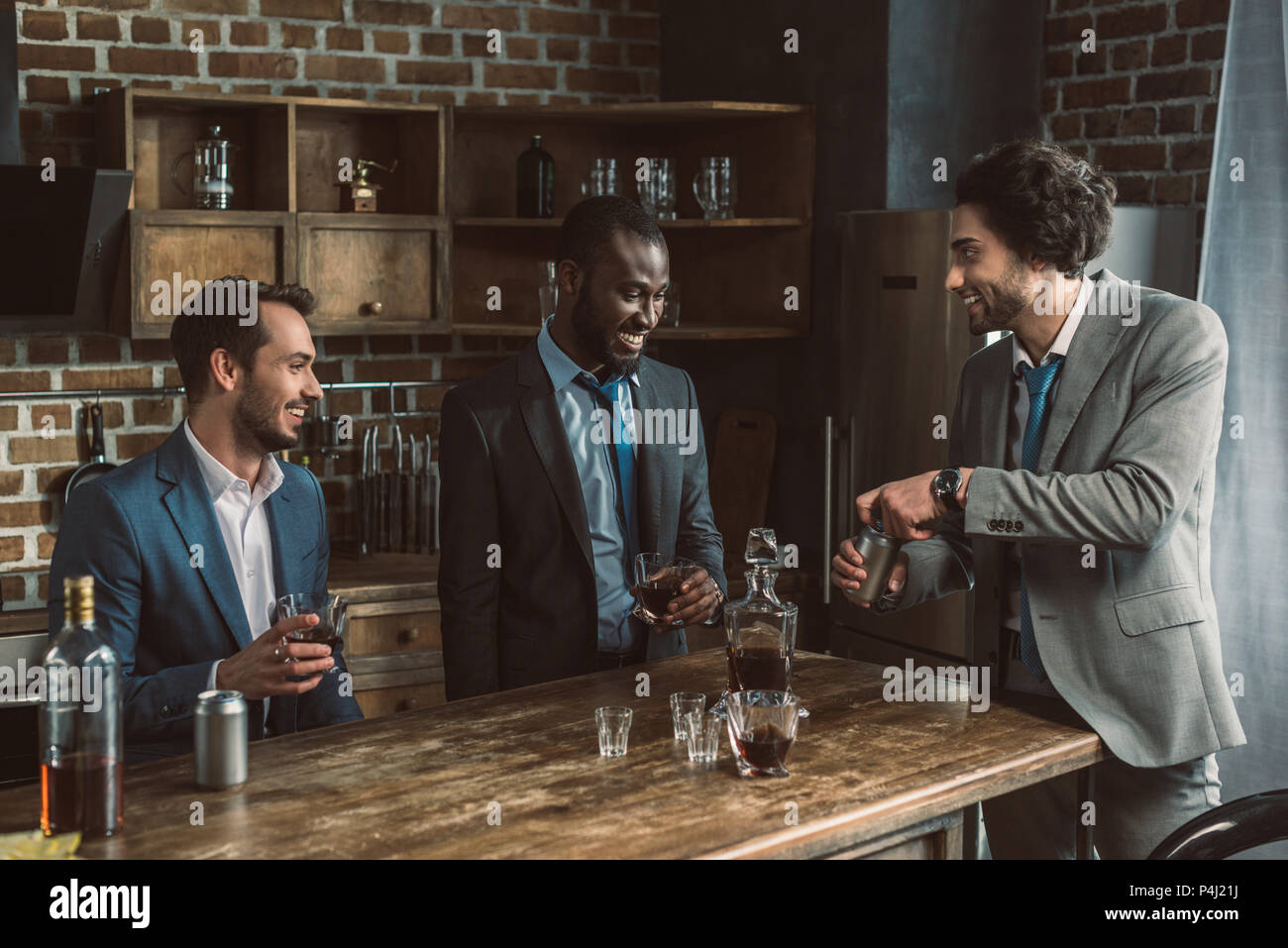 three young multiethnic businessmen drinking alcoholic beverages and ...