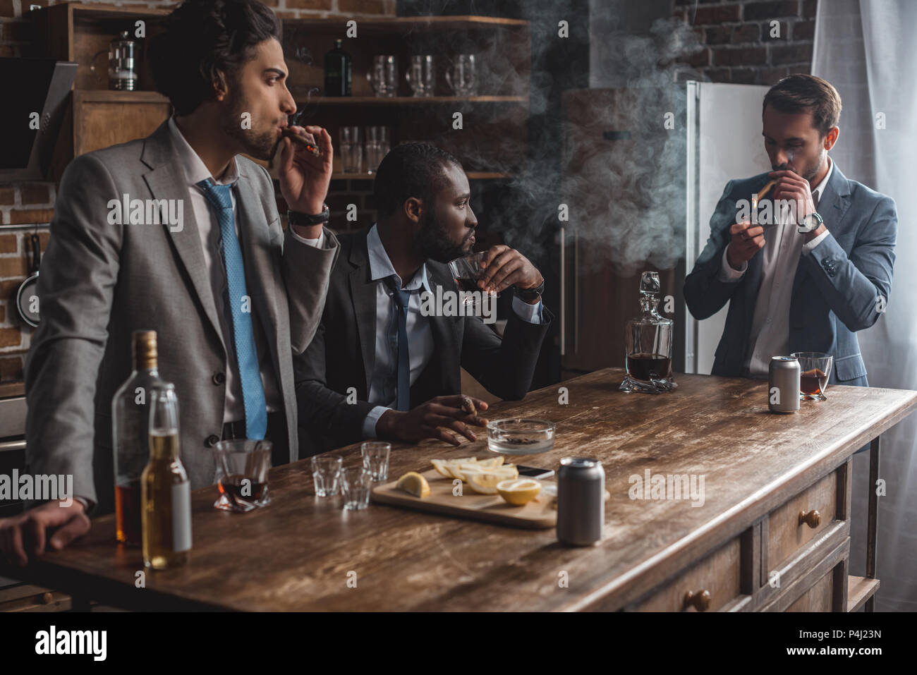 young multiethnic businessmen smoking cigars and drinking alcohol while ...