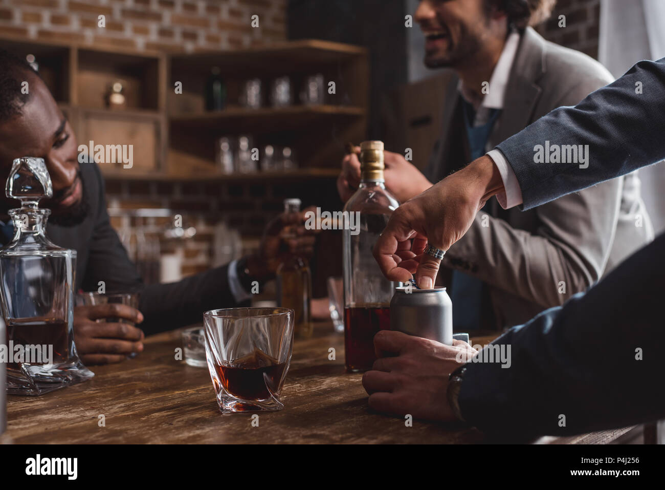 cropped shot of multiethnic men in suits drinking alcoholic beverages ...