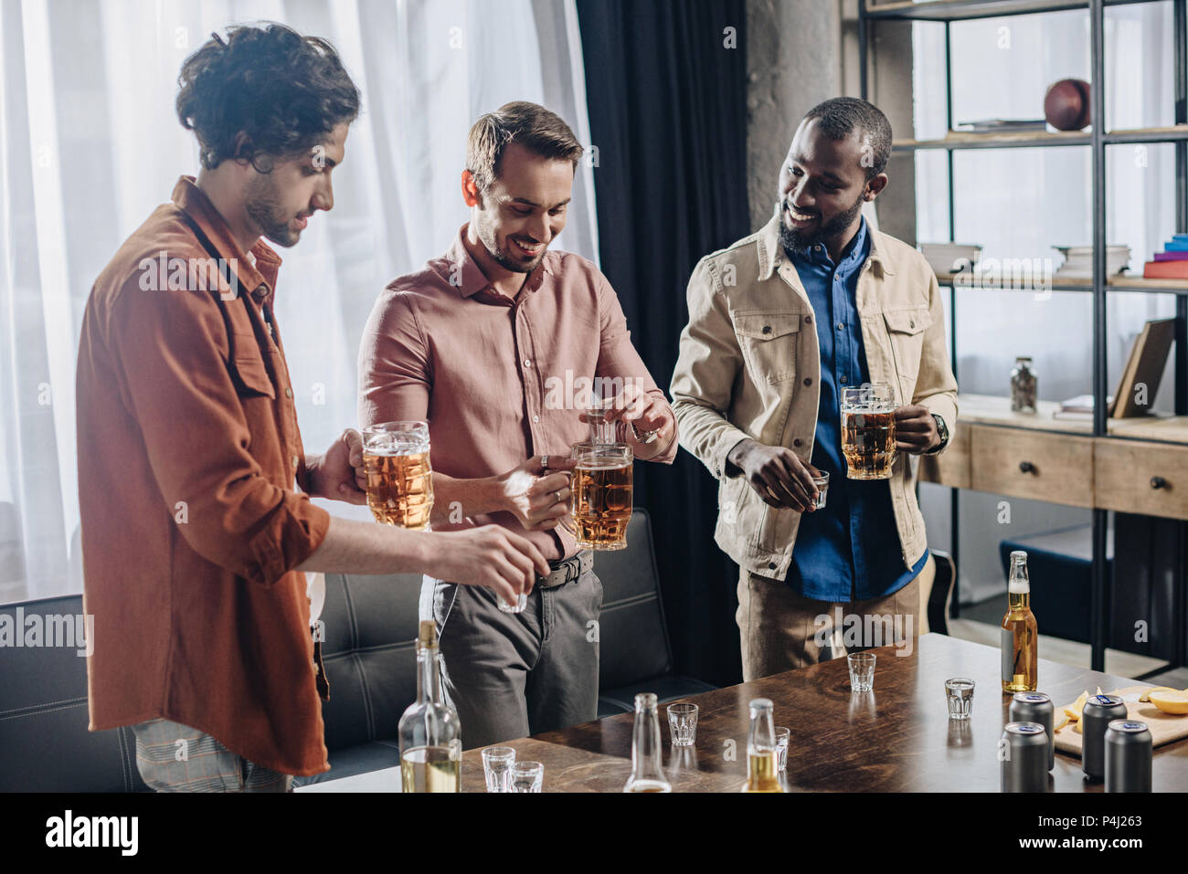 smiling multiethnic male friends drinking alcoholic beverages and ...