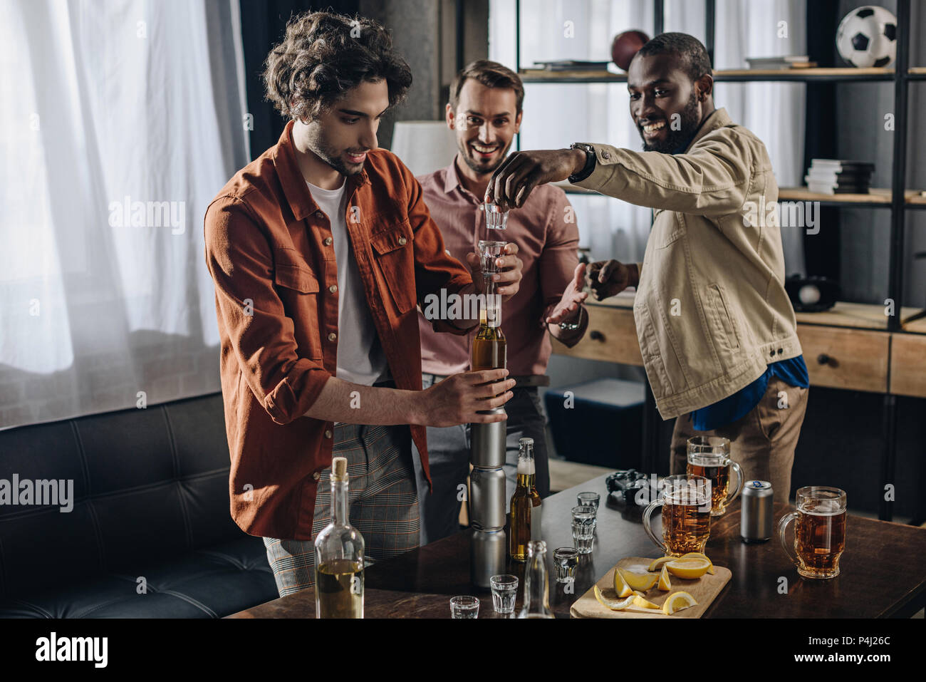 happy multiethnic male friends building tower from glasses and cans ...