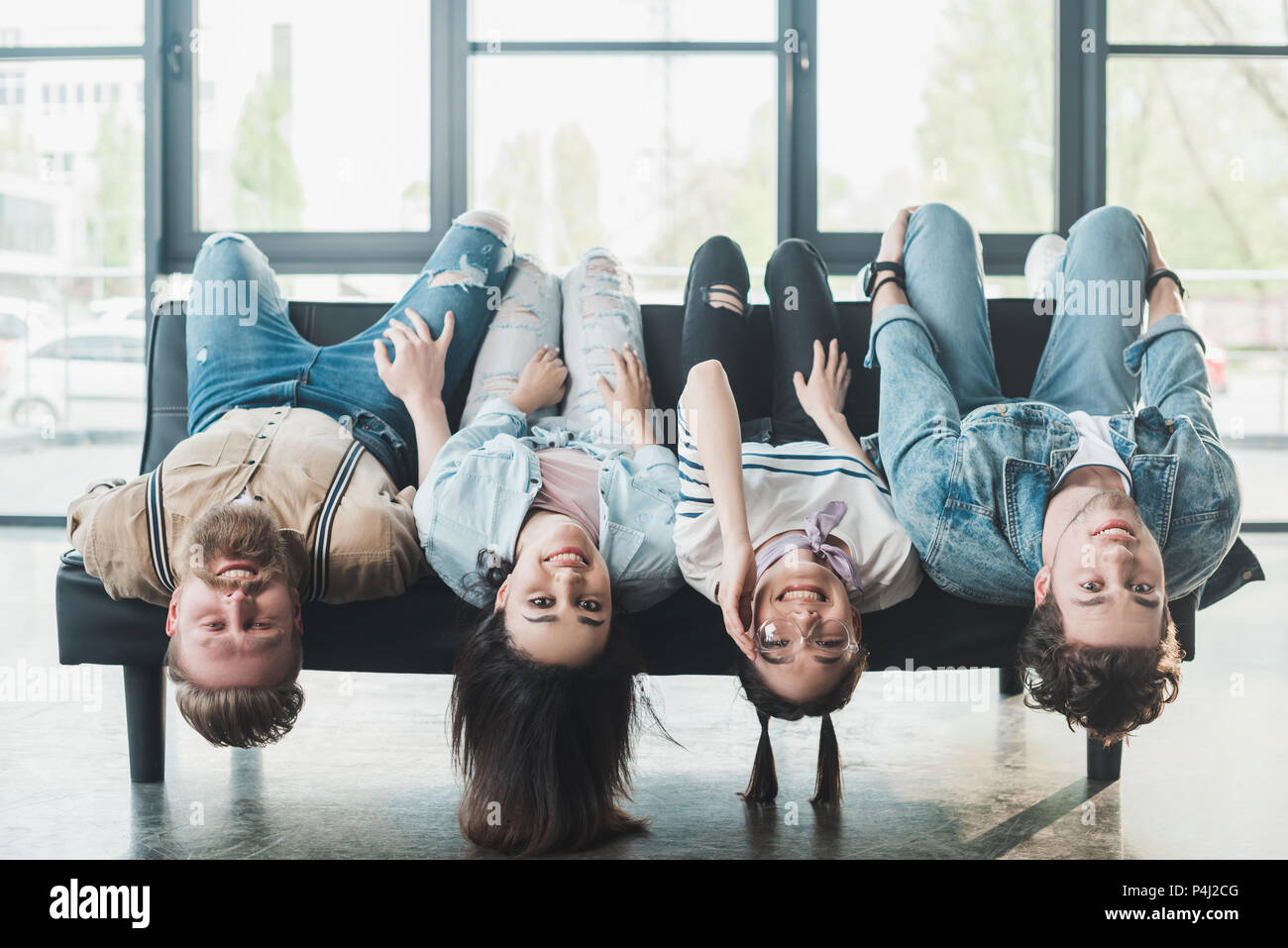 Smiling business people fooling around on sofa in modern light office ...
