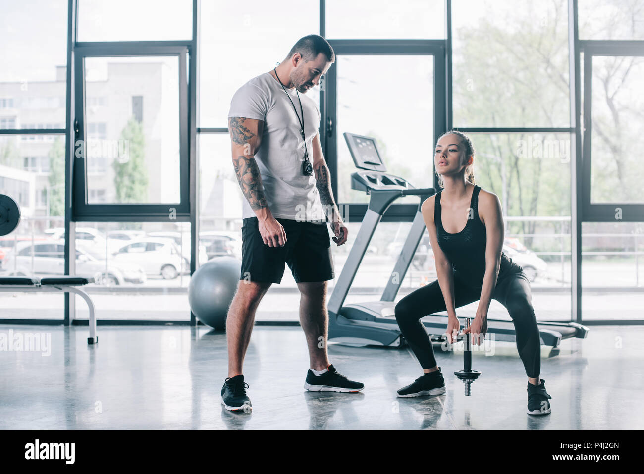 male personal trainer looking at sportswoman doing exercises with ...