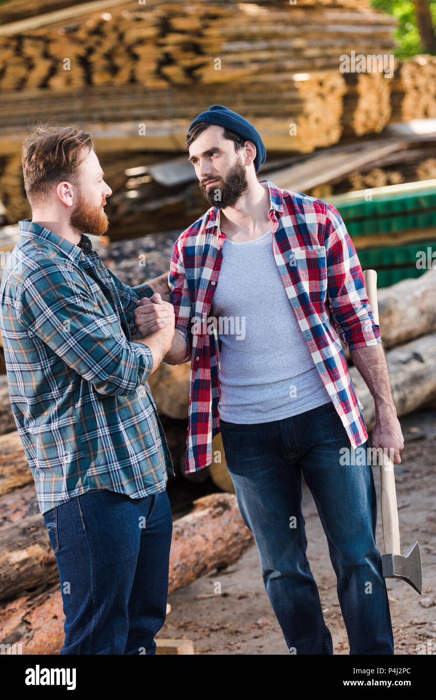 bearded lumberjack in checkered shirt holding axe and shaking hands ...