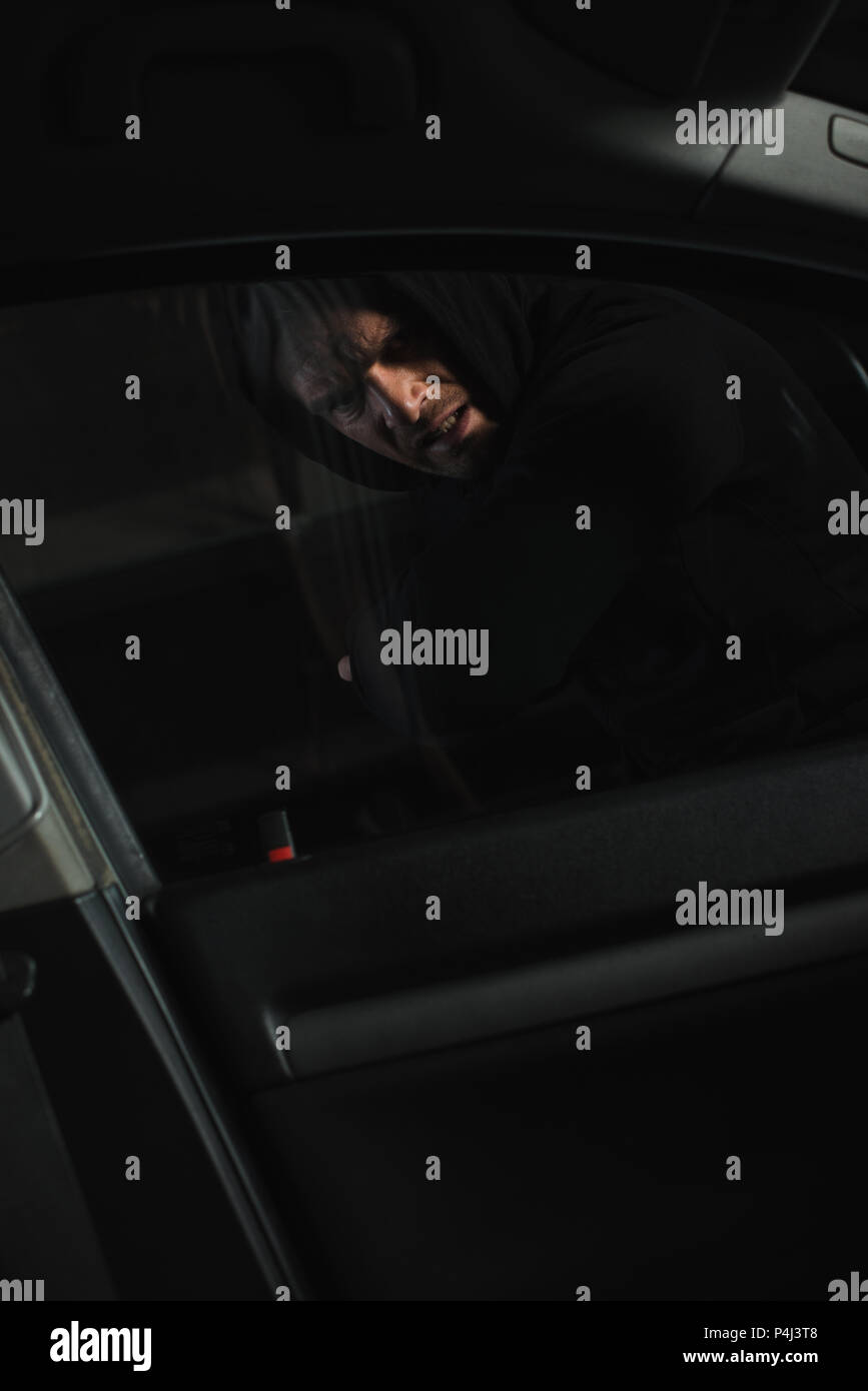 concentrated male robber breaking car window by elbow Stock Photo - Alamy