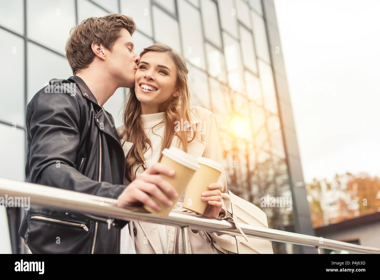 Boyfriend kissing girlfriend standing and leaning on railing Stock ...