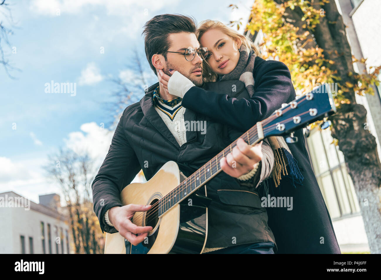 beautiful young woman hugging handsome boyfriend playing guitar on ...