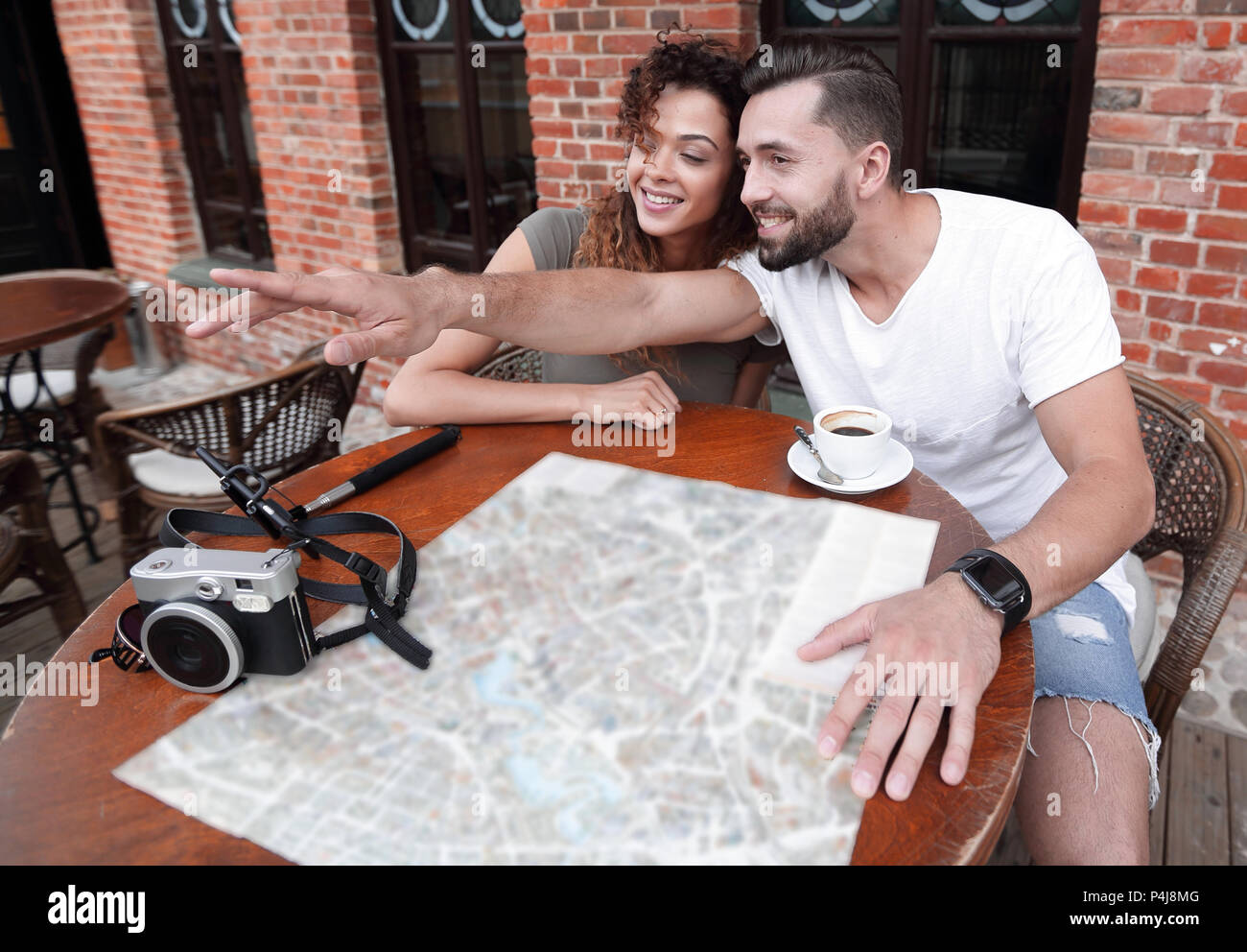 Young tourists drinking coffee at cafe and reading city map Stock Photo ...