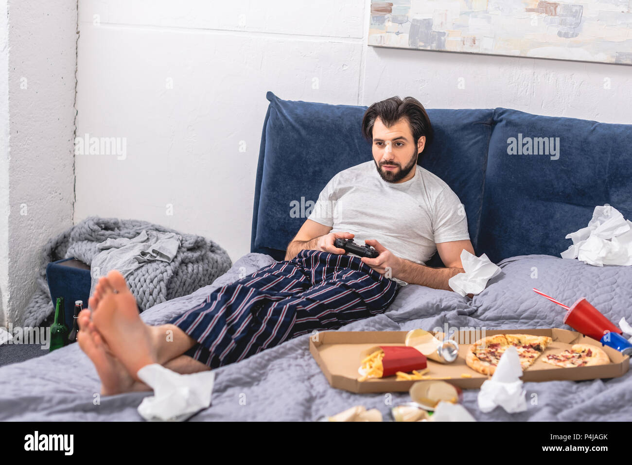 male loner playing video game on bed in bedroom Stock Photo - Alamy