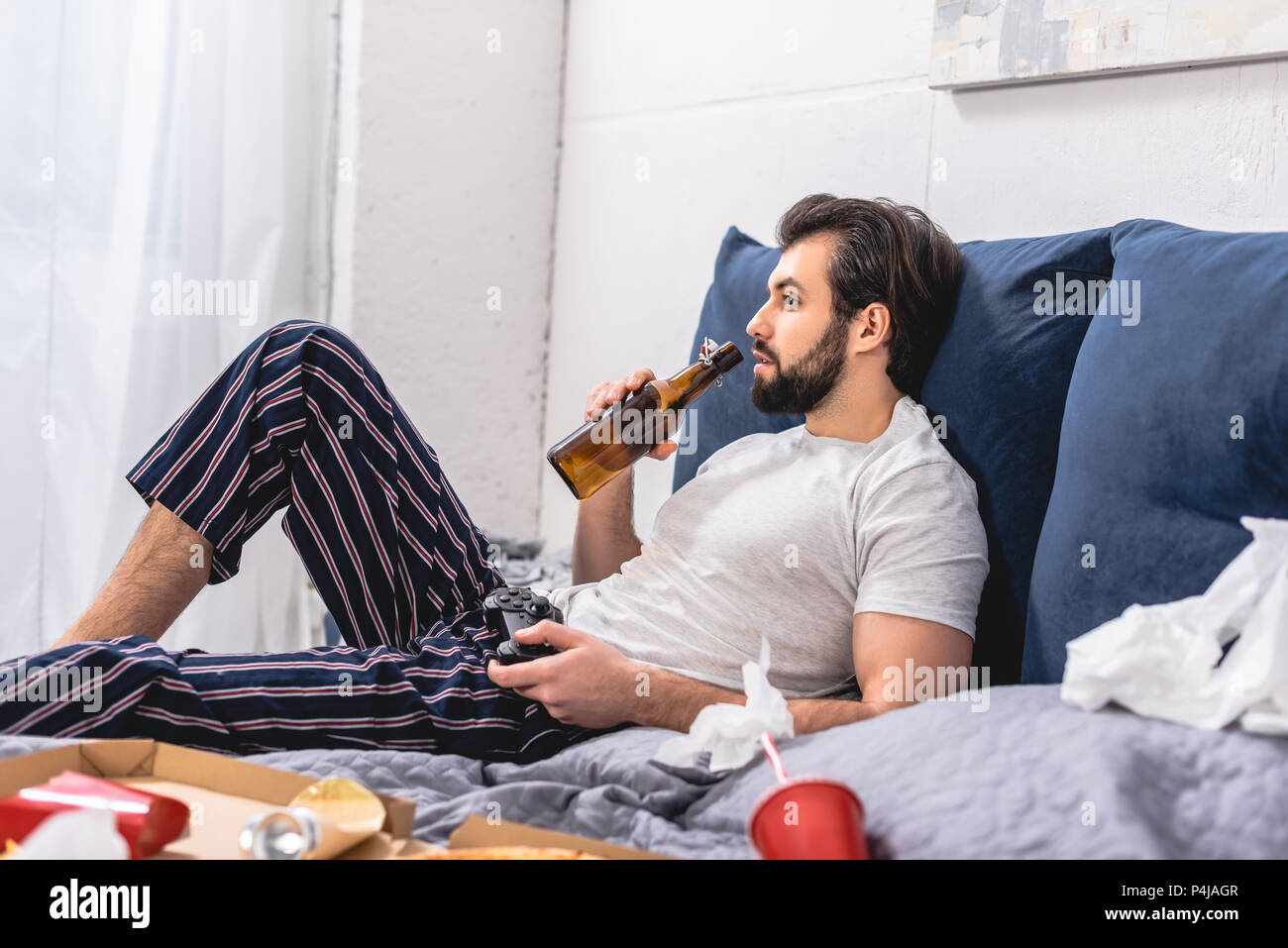 male loner playing video game in bedroom and drinking beer Stock Photo ...