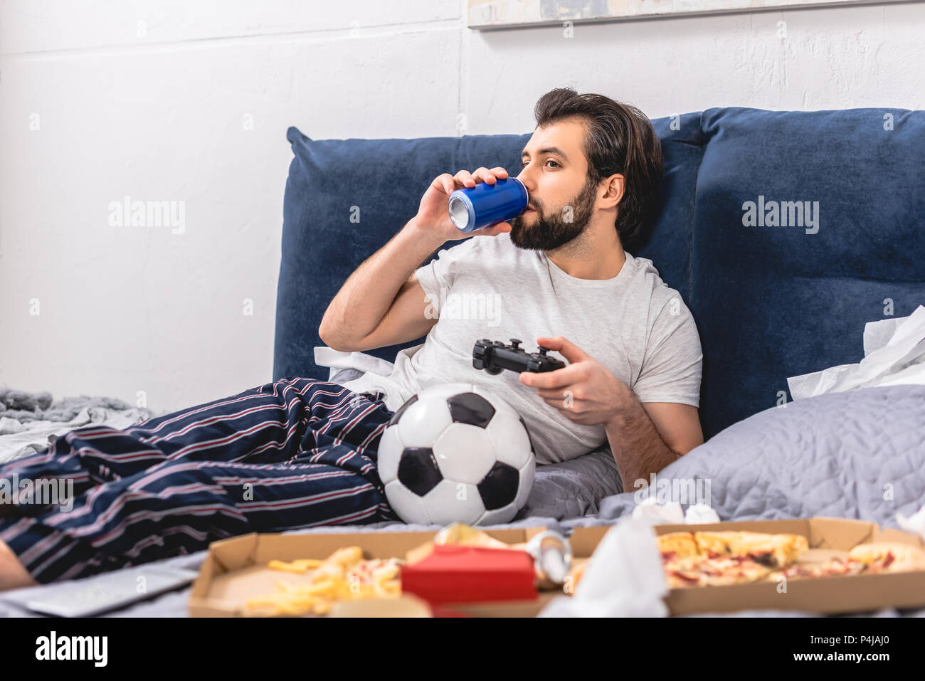 male loner playing video game and drinking beverage in bedroom Stock ...